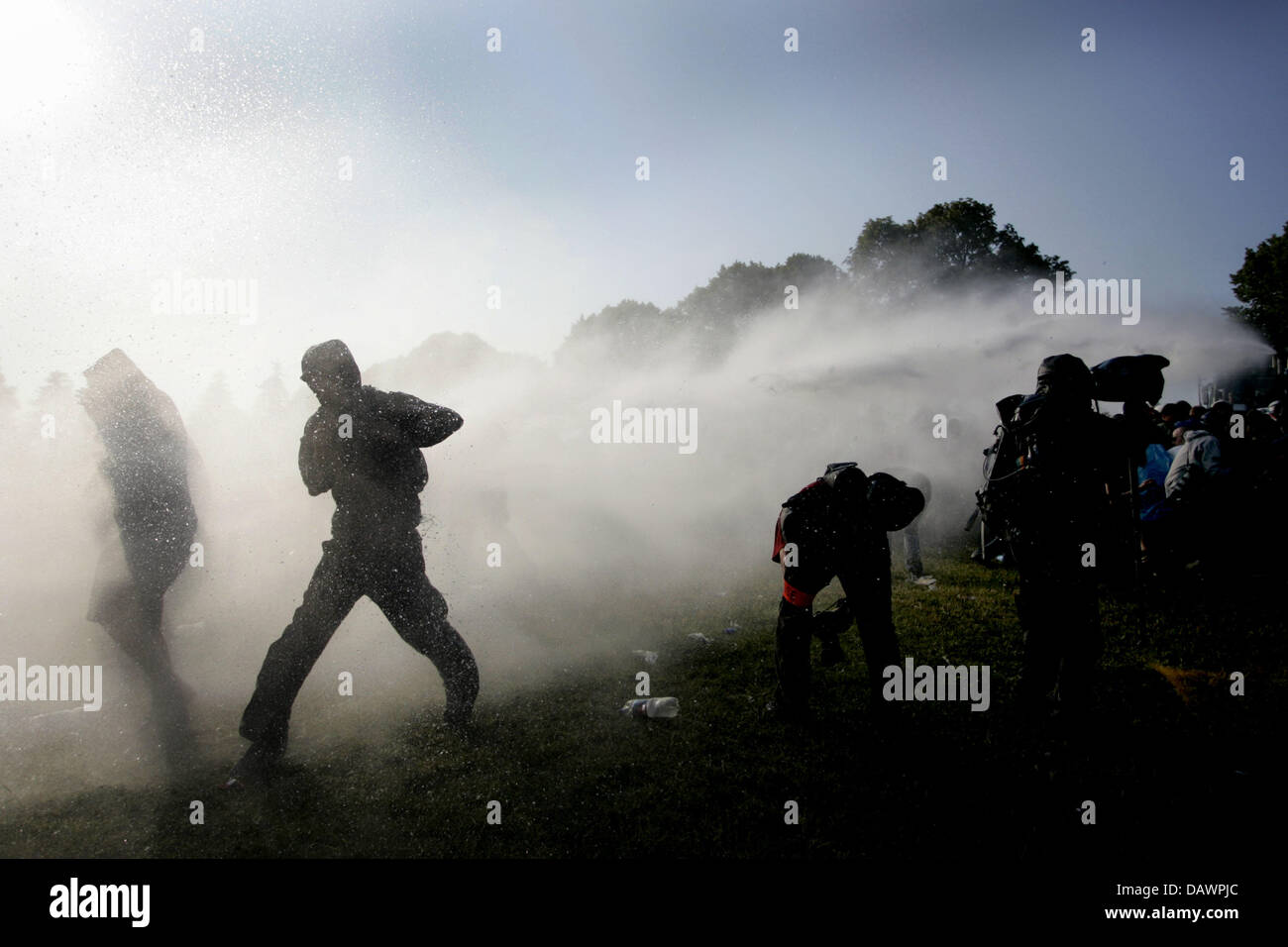 Anti-G8 activists seek shelter from a police water cannon jet near ...