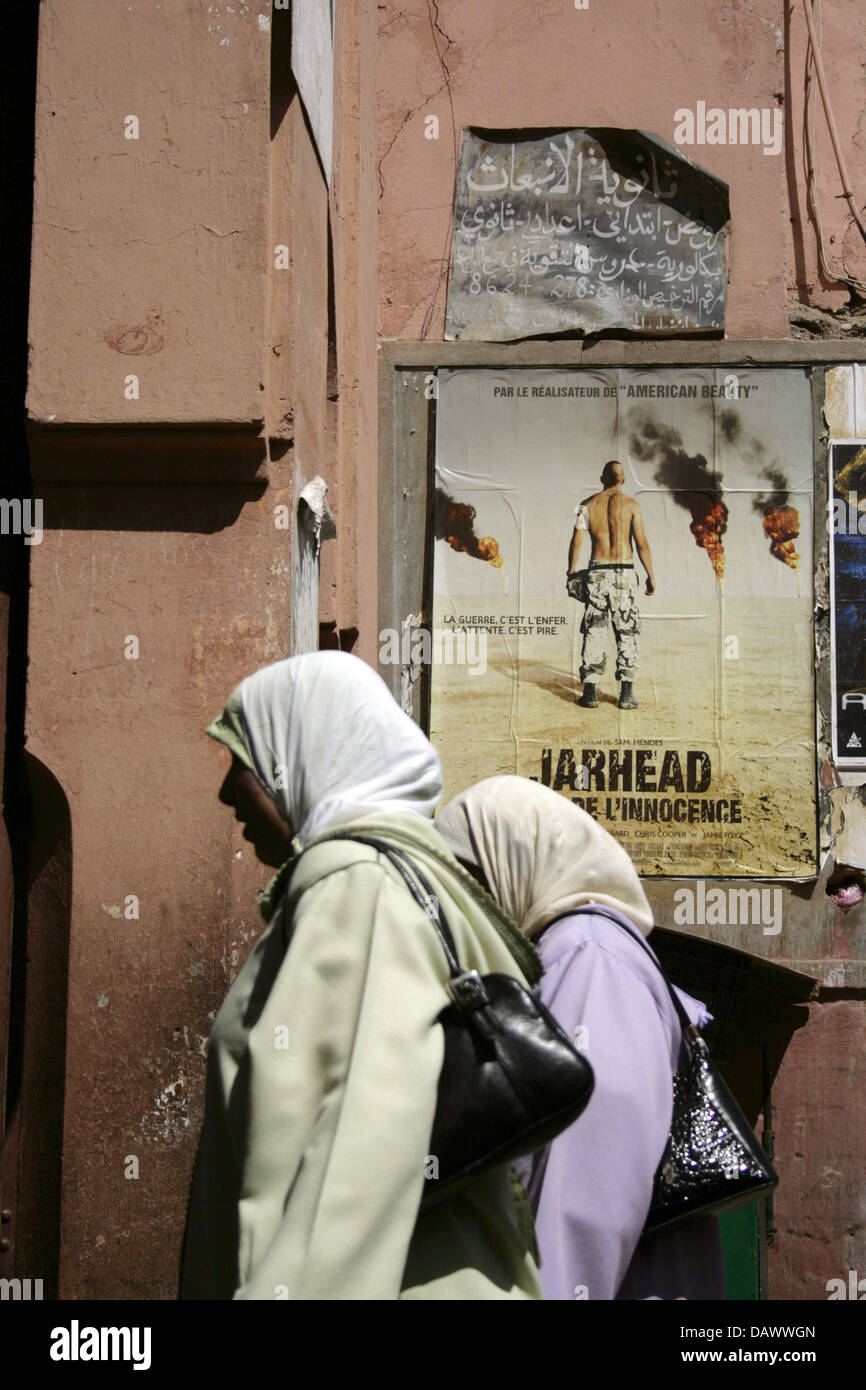 Two women with head scarves pass a film poster of 'Jarhead' in the ...