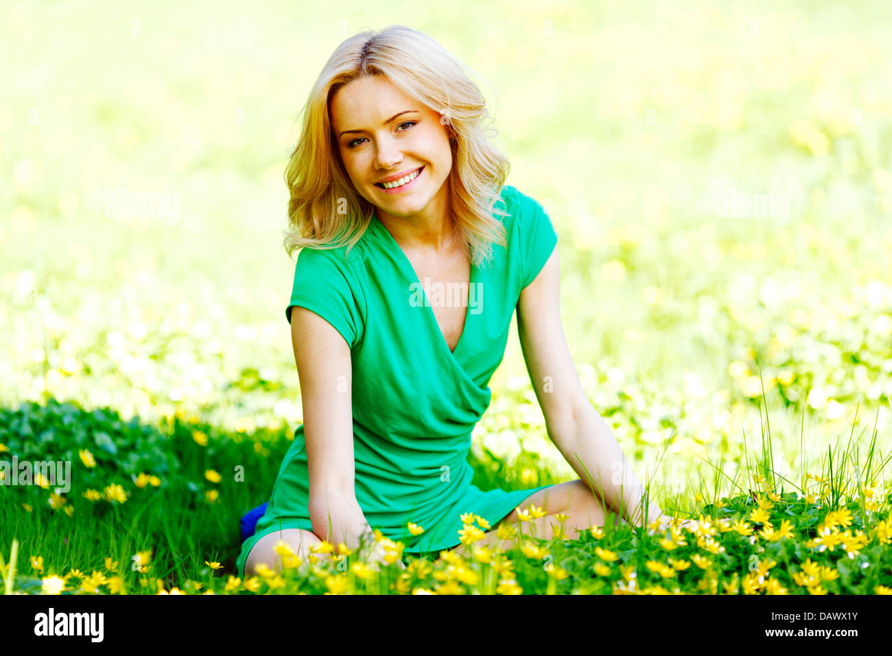 Beautiful young woman sitting on flower field Stock Photo - Alamy