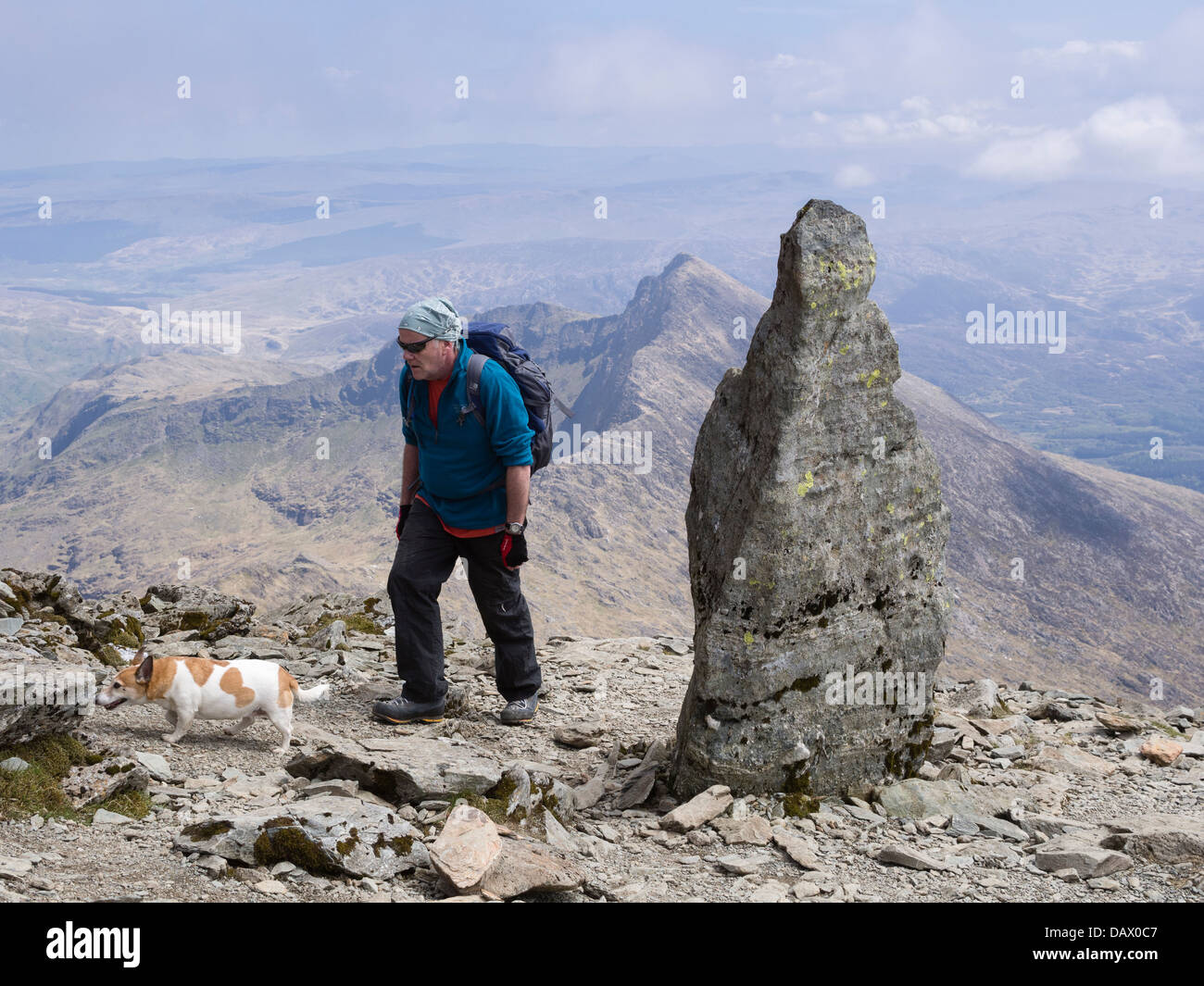 Walker with dog by stone marker at top of Watkin path on Snowdon south ...
