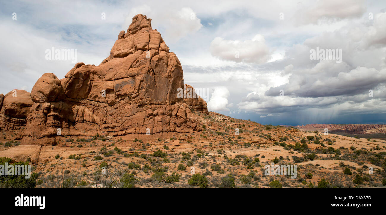 A rock spire and spring rain storm in a desert valley of Arches ...
