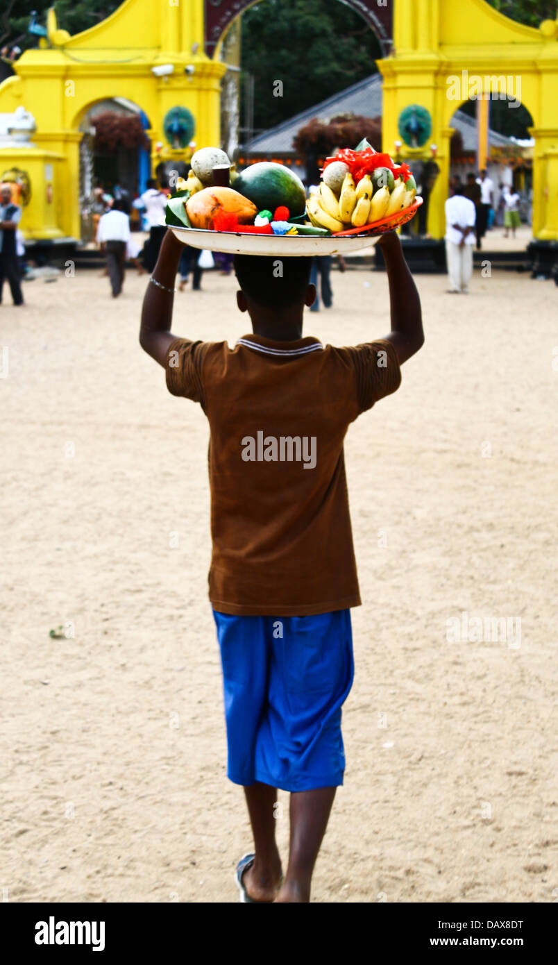 A boy carries an offering of fruit towards a temple in Katarama ...
