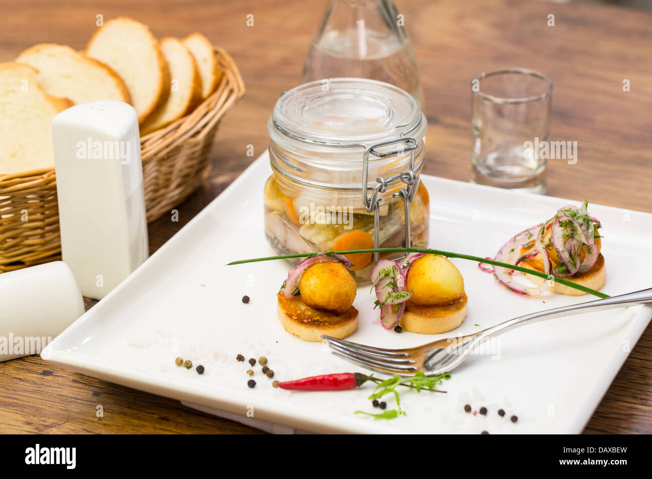 pickled herring in a glass jar with potato canapes Stock Photo - Alamy
