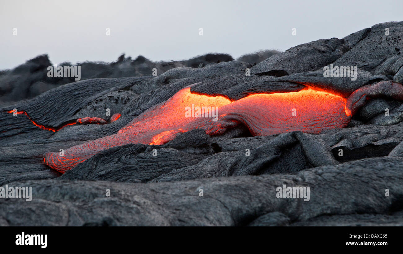 Fresh lava breaks through the crust formed by earlier lava flows at the ...