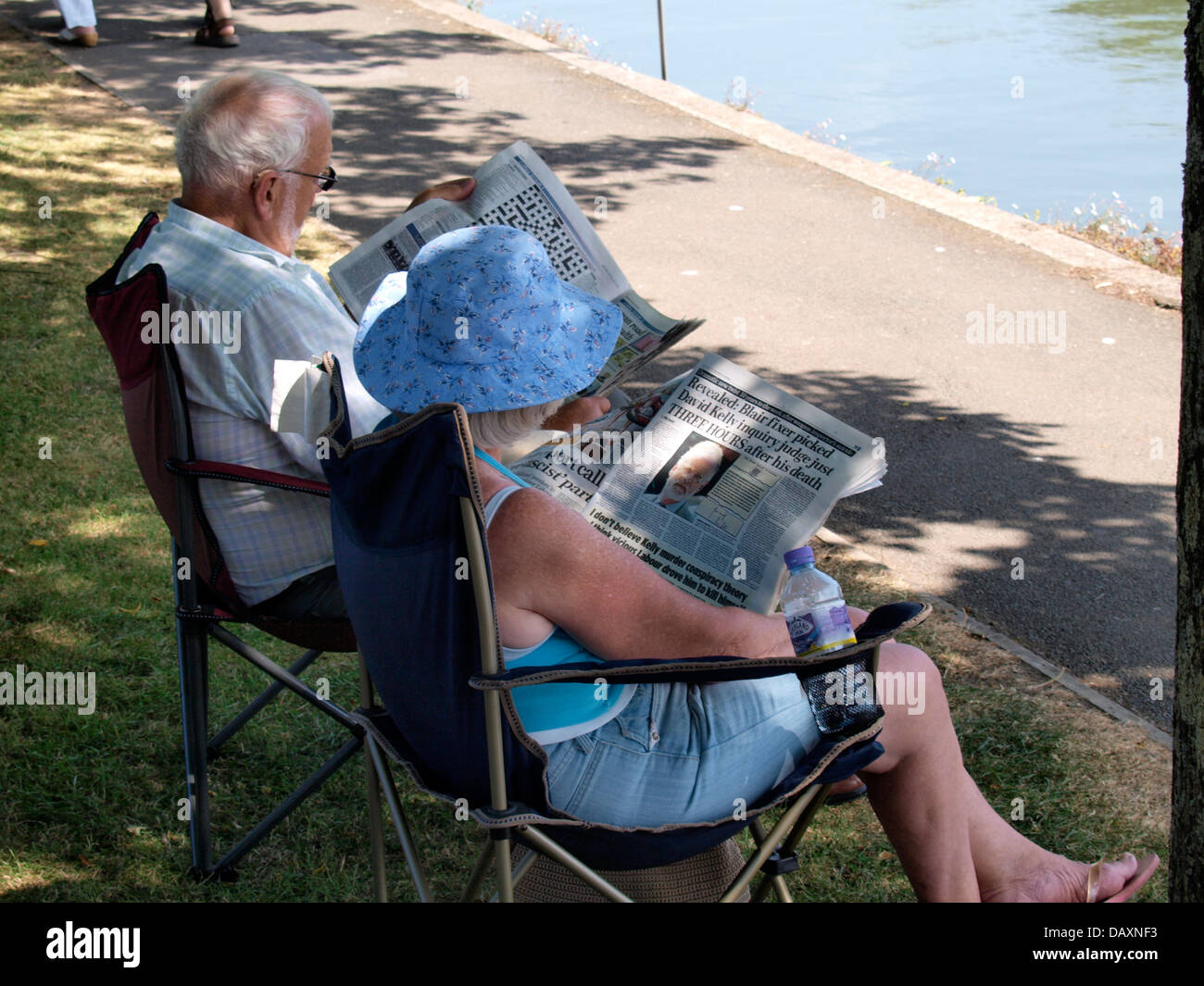 Old couple sat in the shade of a tree reading newspapers, Kingsbridge ...
