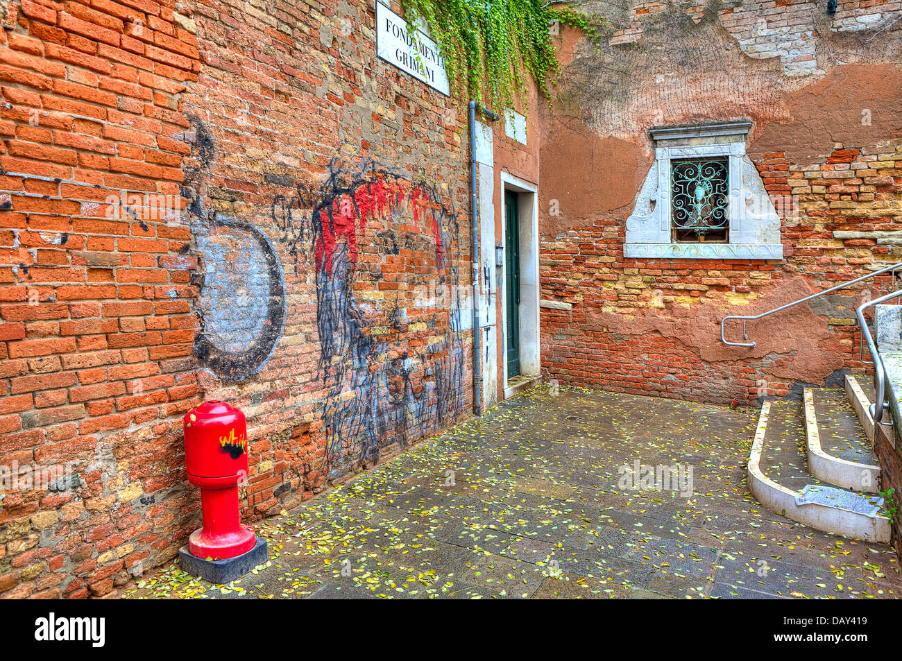 Small courtyard among old red brick walls with graffiti in Venice ...