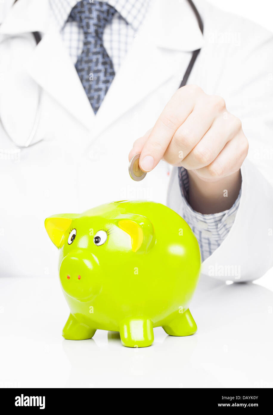 Medical doctor putting a coin into piggy bank as an idea for healthcare ...