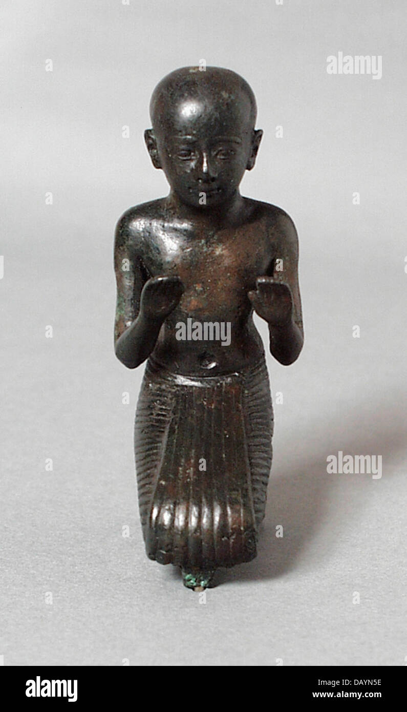 This figurine depicts a priest in a kneeling, worshipful pose ...