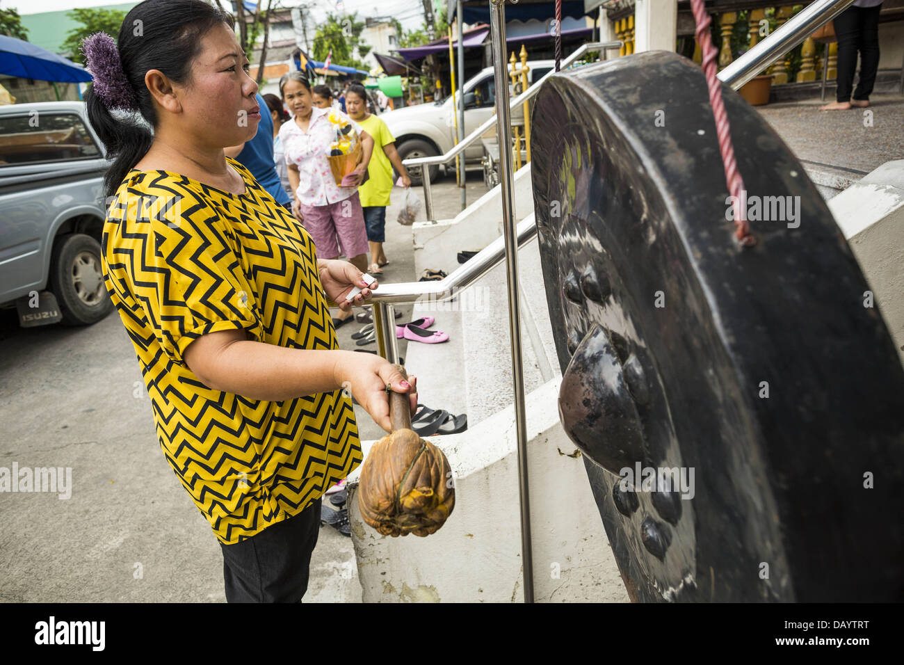Bangkok, Thailand. 21st July, 2013. A woman hits a prayer gong at Wat ...