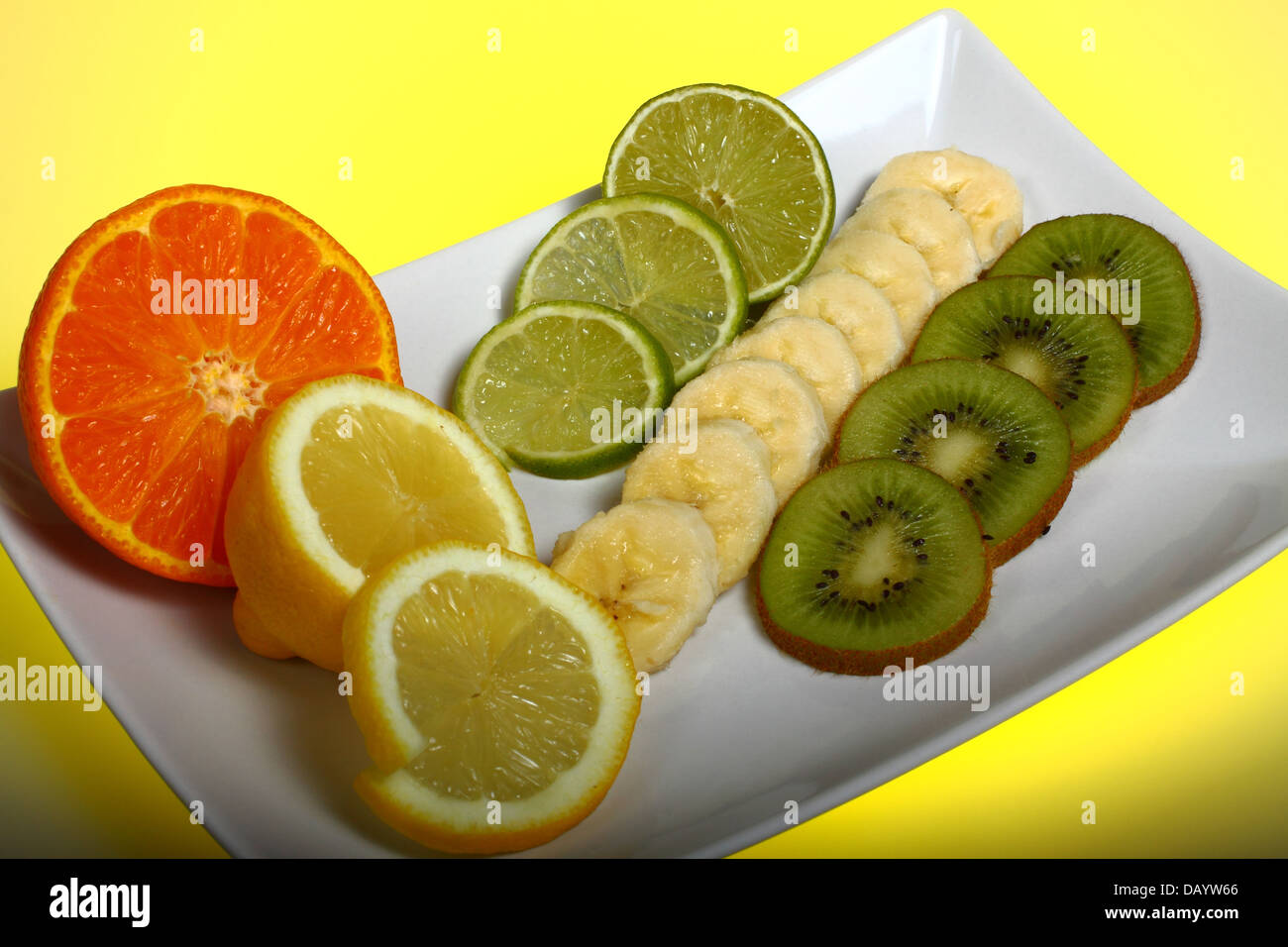 Selection of fruit on a plate with yellow background Stock Photo - Alamy