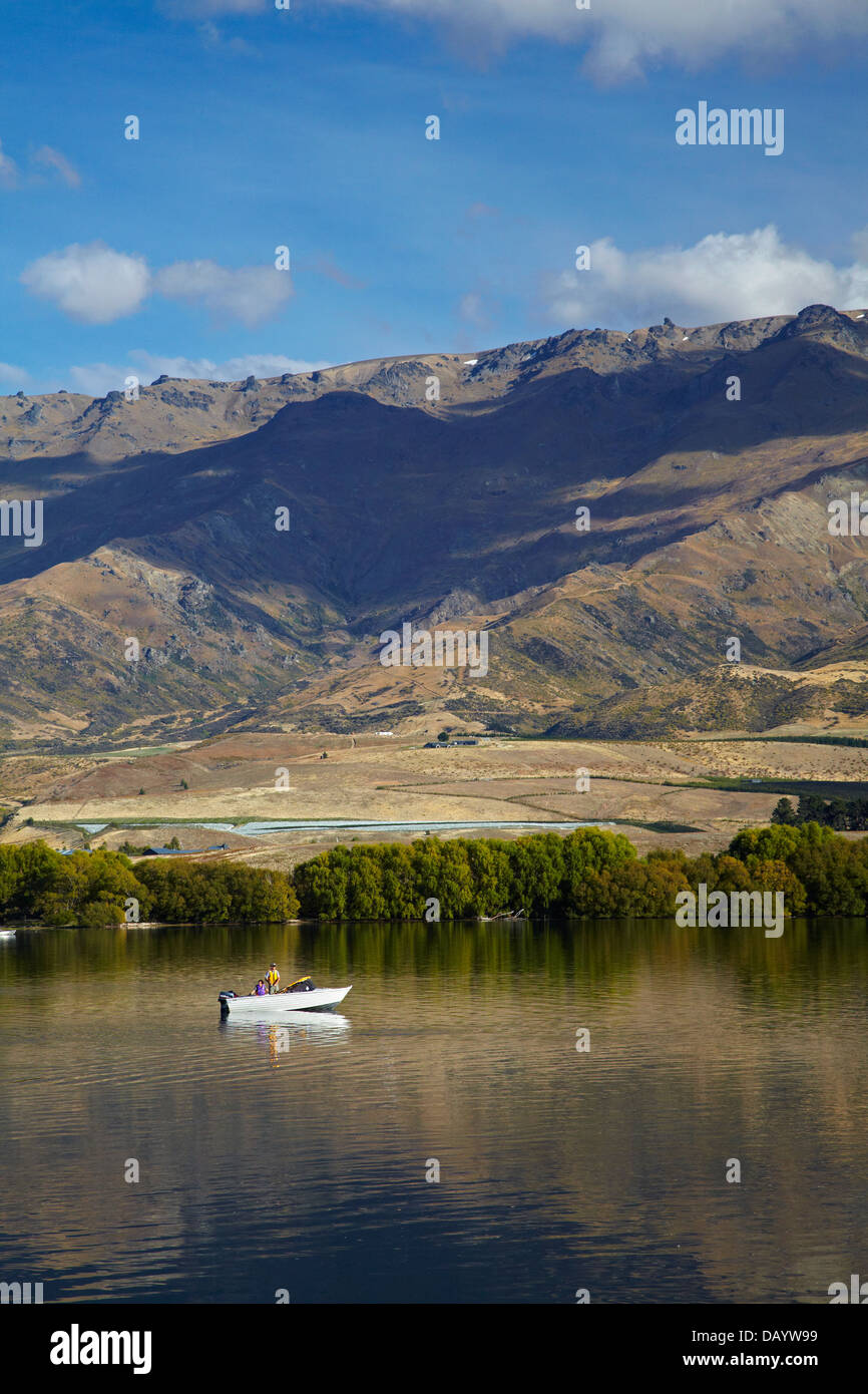 Lake Dunstan, Pisa Range, and people in boat fishing, Central Otago ...