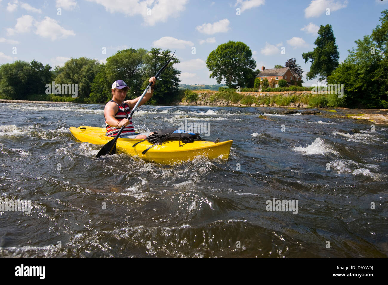 Canoeist in kayak type yellow canoe paddling down the River Wye at Hay ...