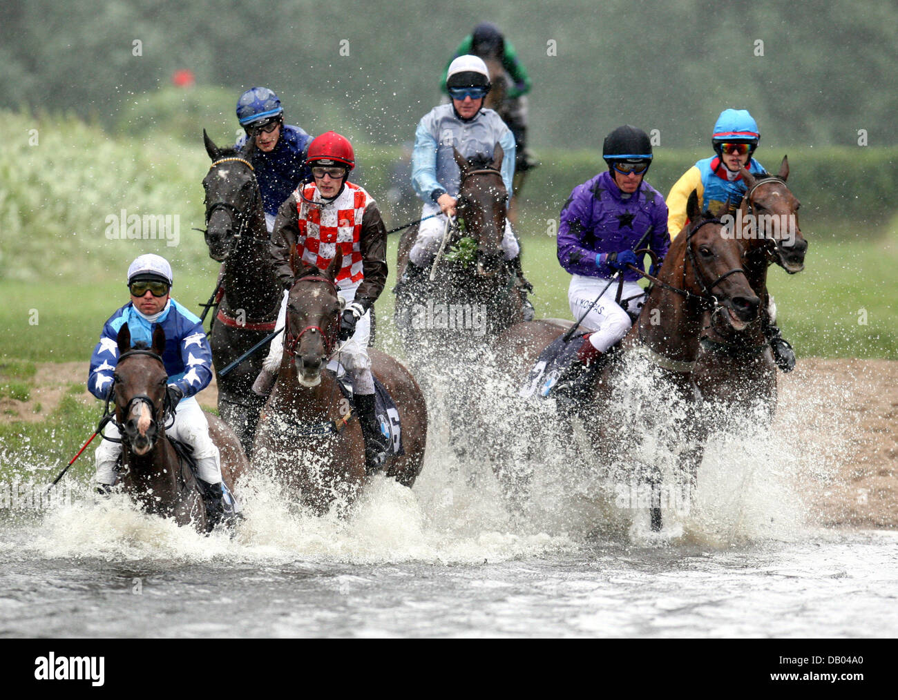 Riders and horses cross the lake during the steeplechase at the 138th ...