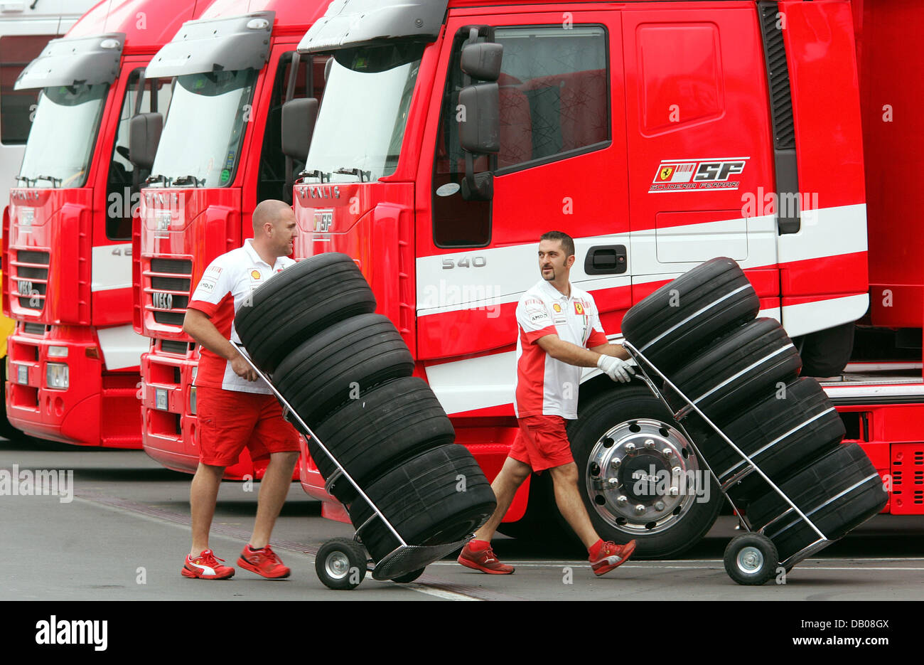 Ferrari mechanics push trolleys with tires through the paddock at race ...