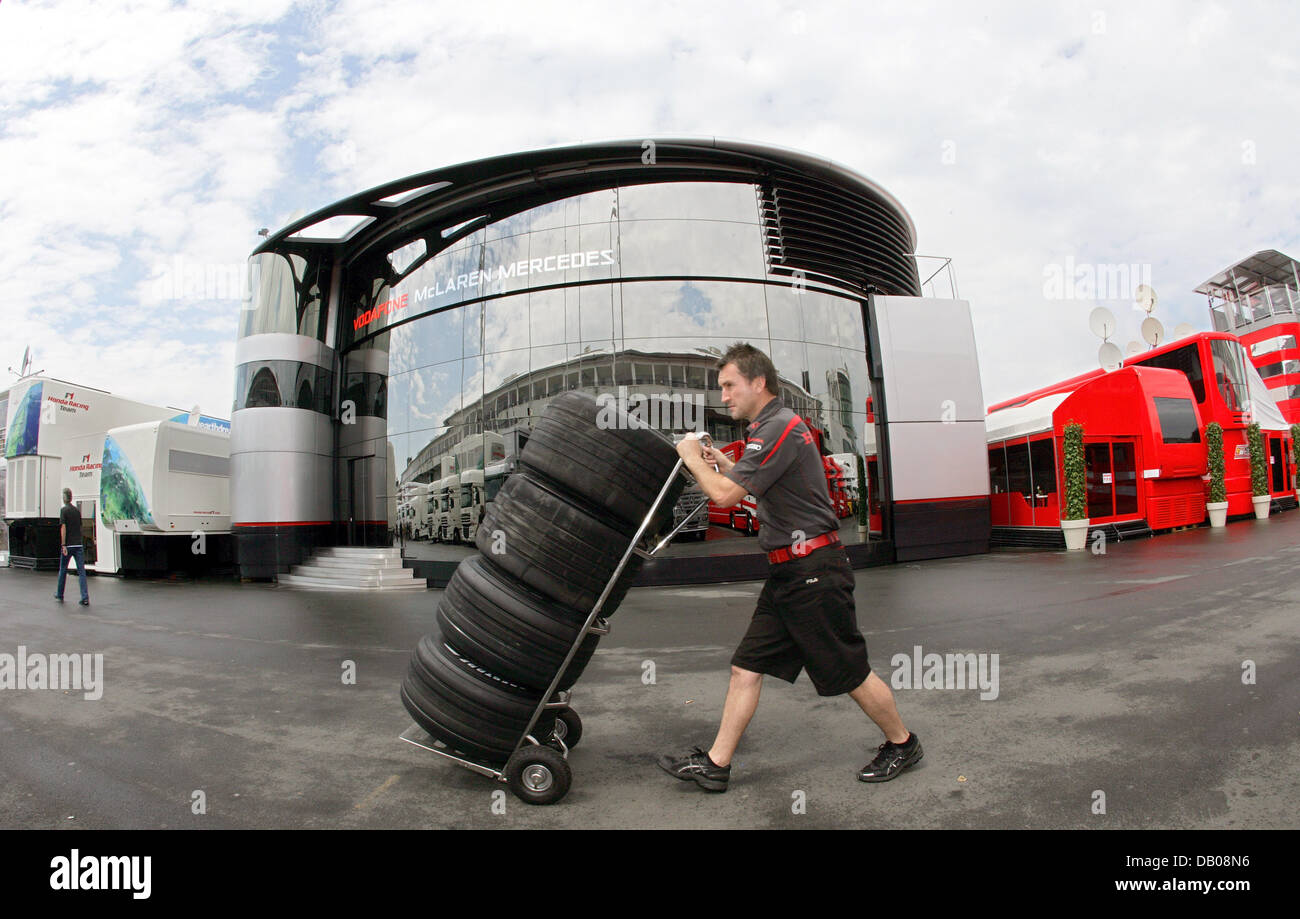 A mechanic pushes a trolley with tires through the paddock at the ...