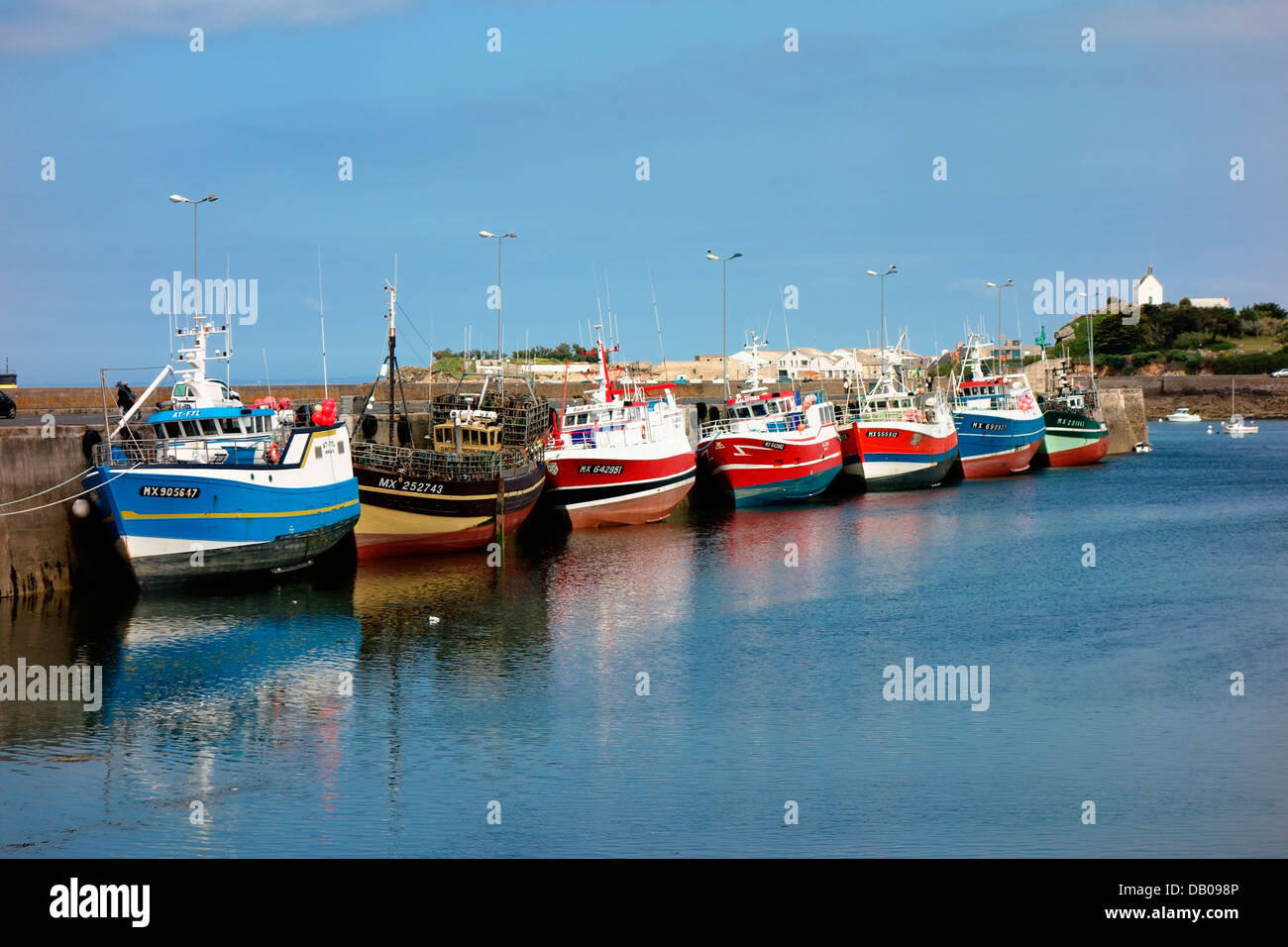 A row of fishing boats a low tide along the harbour wall at Roscoff ...