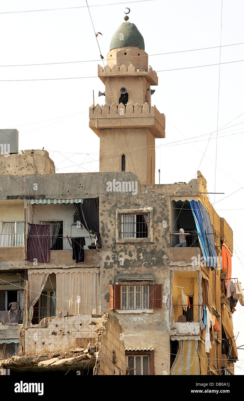 The picture shows a scruffy building in front of a mosque's minaret at ...