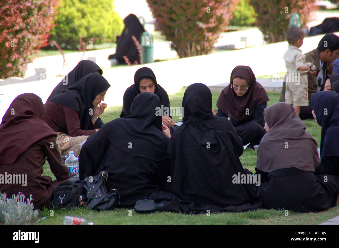 A group of young women dressed in traditional chadors gathers on a ...