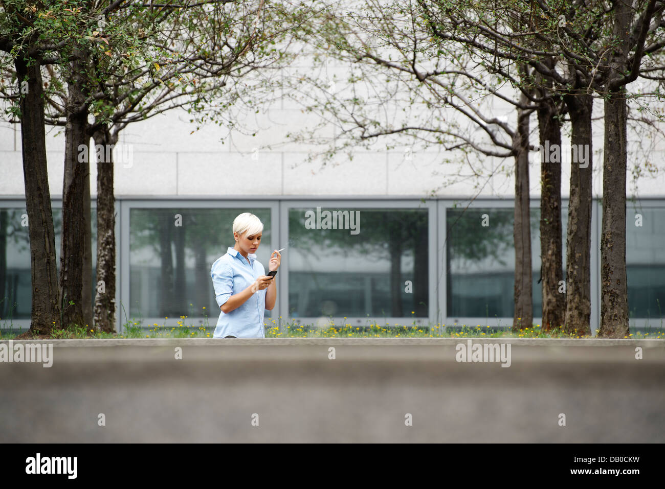 young businesswoman smoking cigarette during break out of office ...