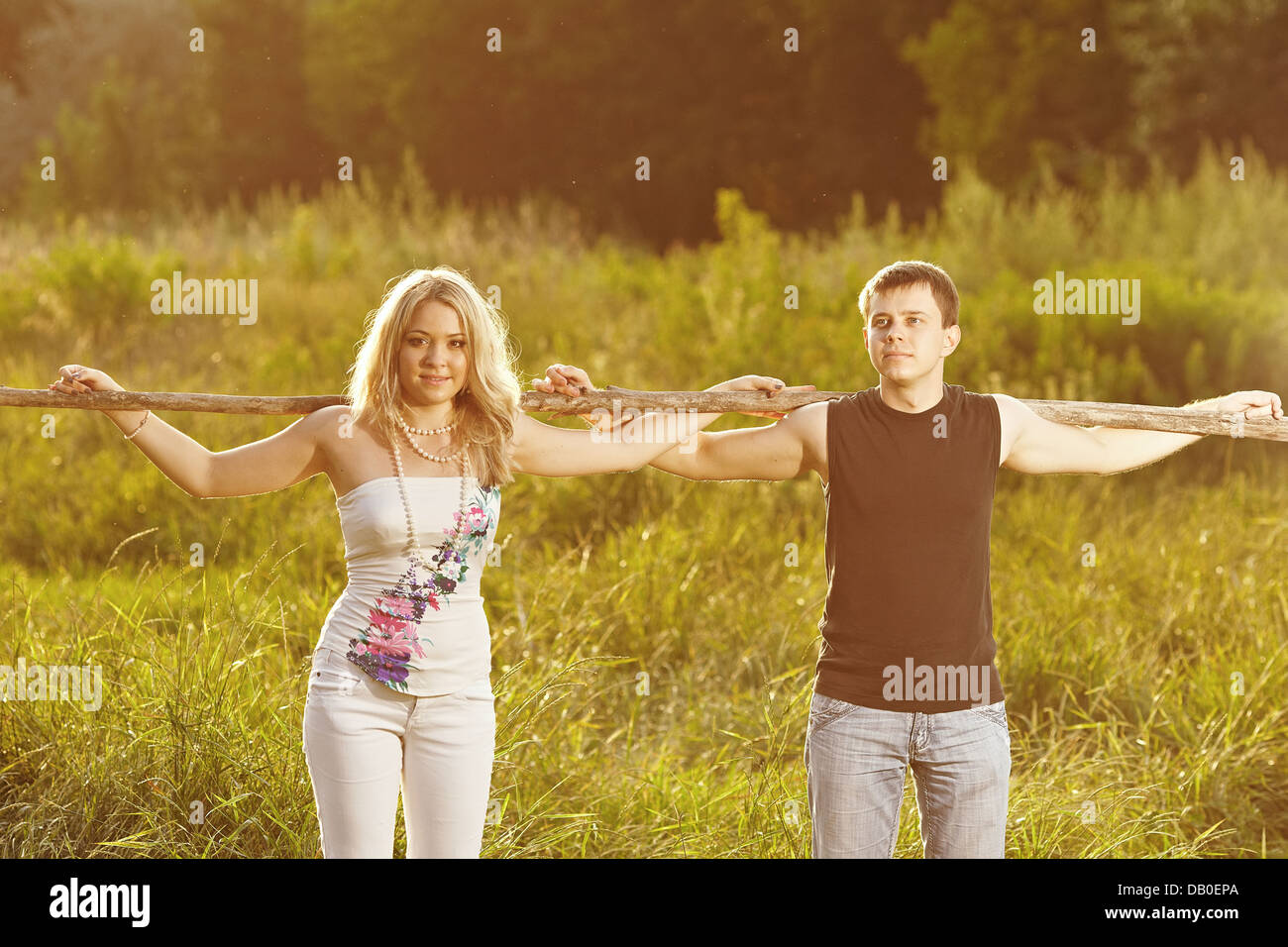 Young couple support each other, holding on to a tree on a background ...