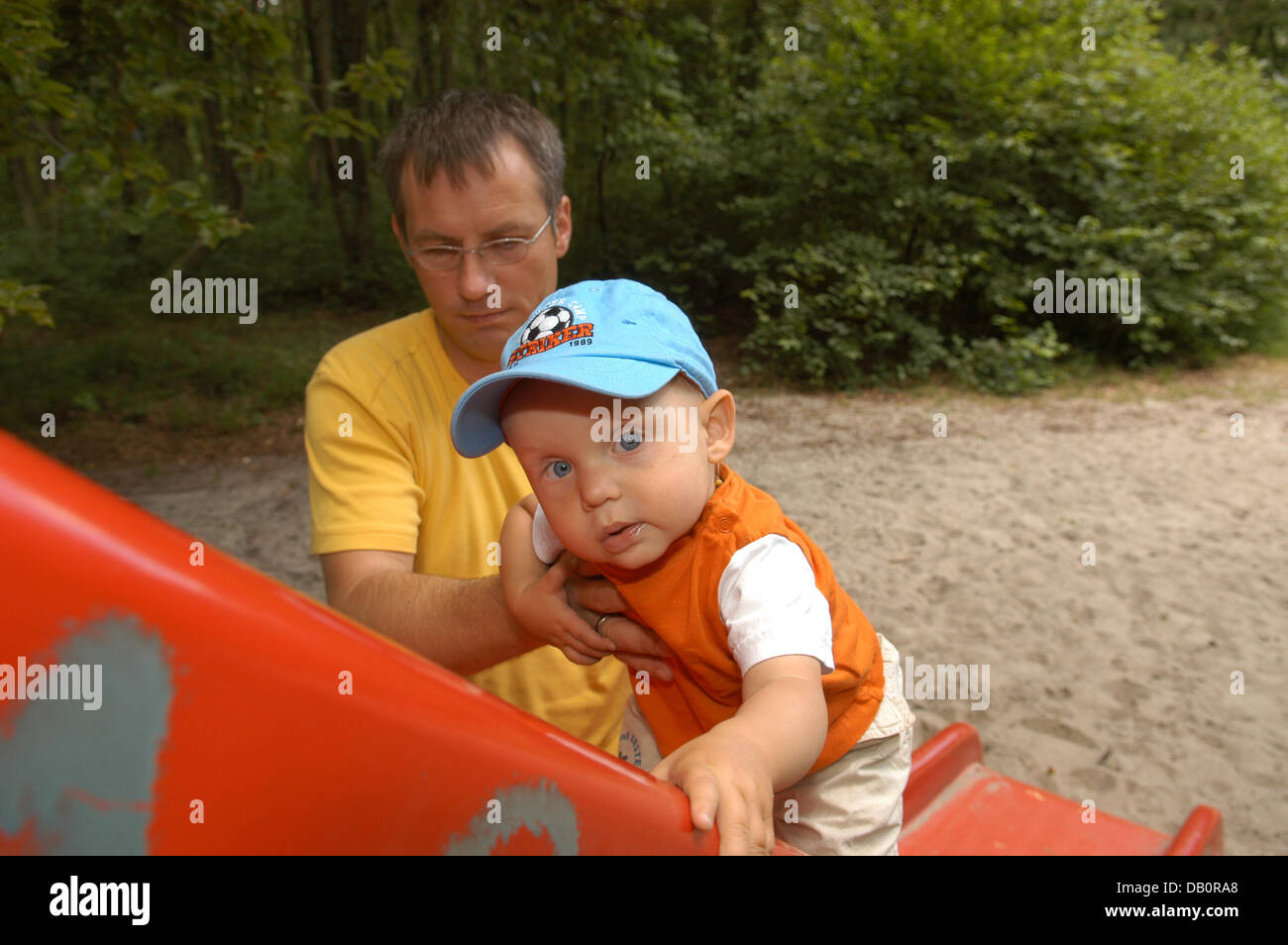 Father Peter Ott and his young son Lukas play on a slide in ...