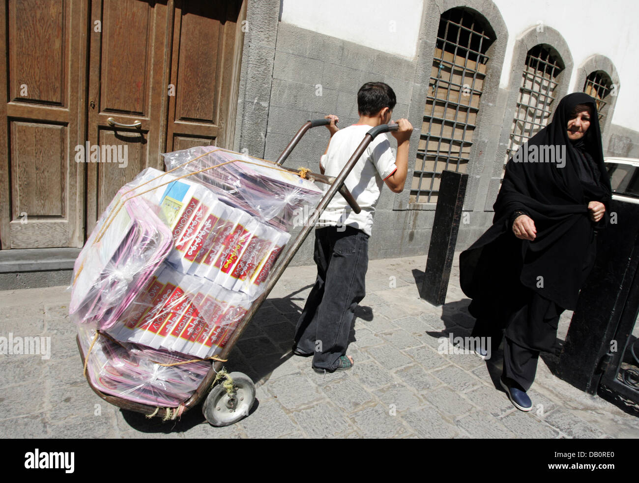 A boy carries a sack barrow with 'Monopoly' games in an old part of ...