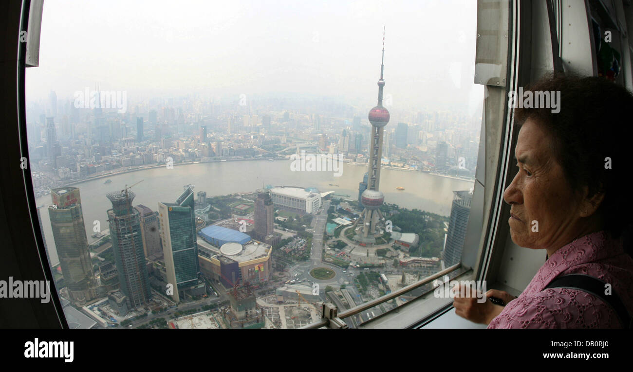 A woman looks at the city skyline through a window of the Jin Mao ...