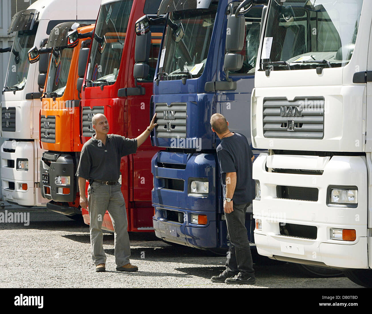 Workers converse in front of a row of brandnew MAN lorries at the MAN ...