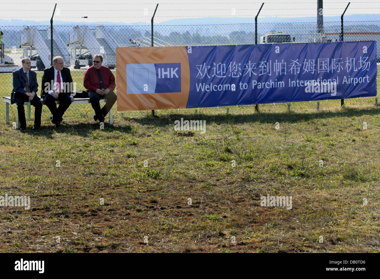 Three men sit beside a banner reading 'Welcome to Parchim International ...