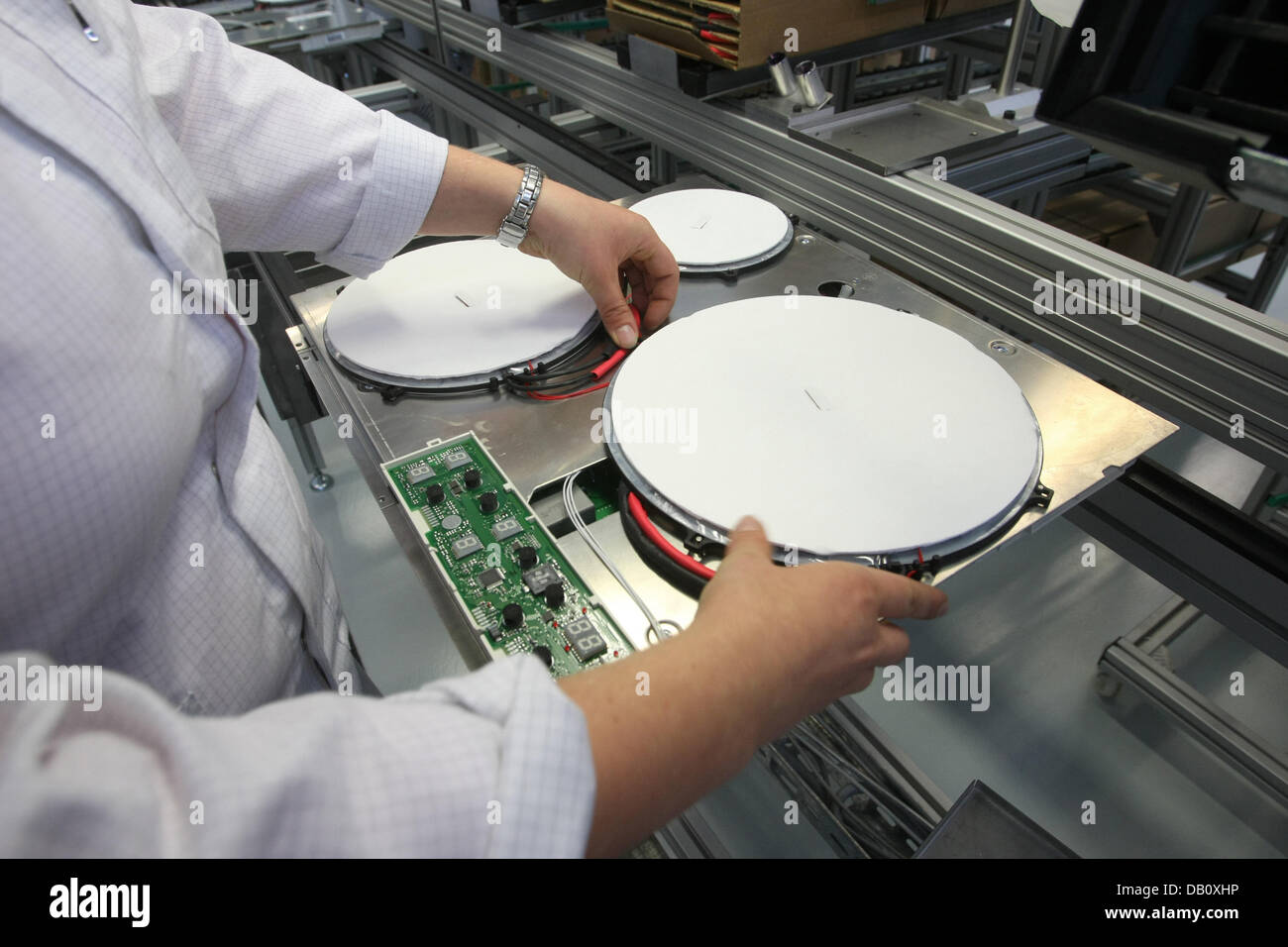 An emplyee does the final assembly of induction cookers manufactured in ...