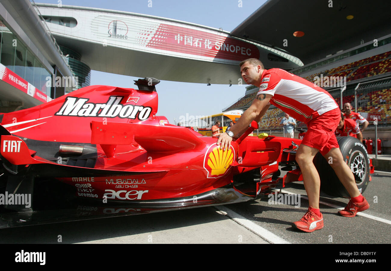 Mechanics of Ferrari push a race car through the pitlane at Shanghai ...