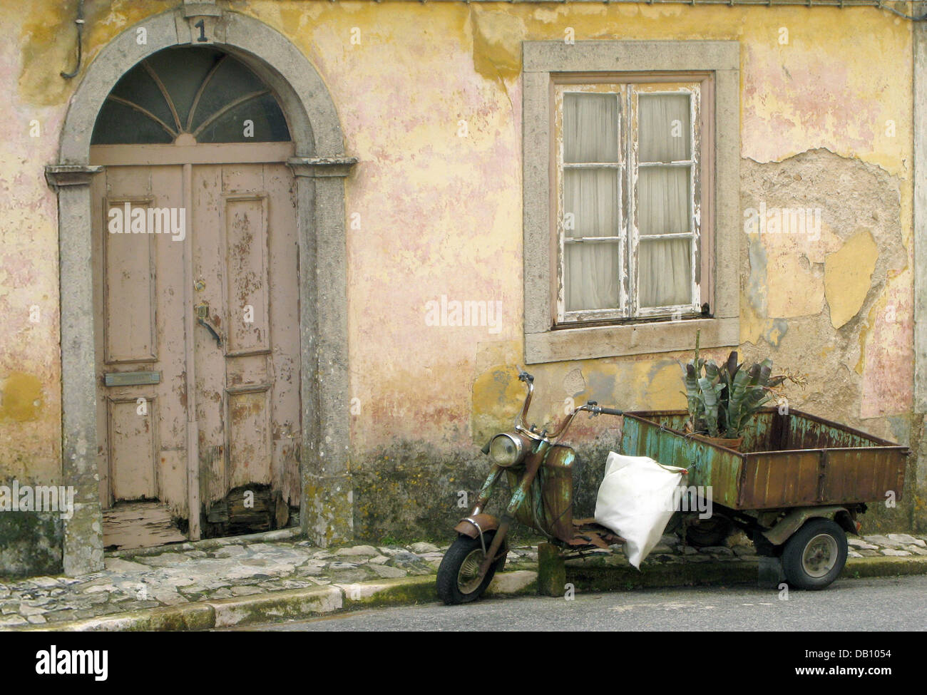A rusty moped with hanger pictured in front of a withered house in ...
