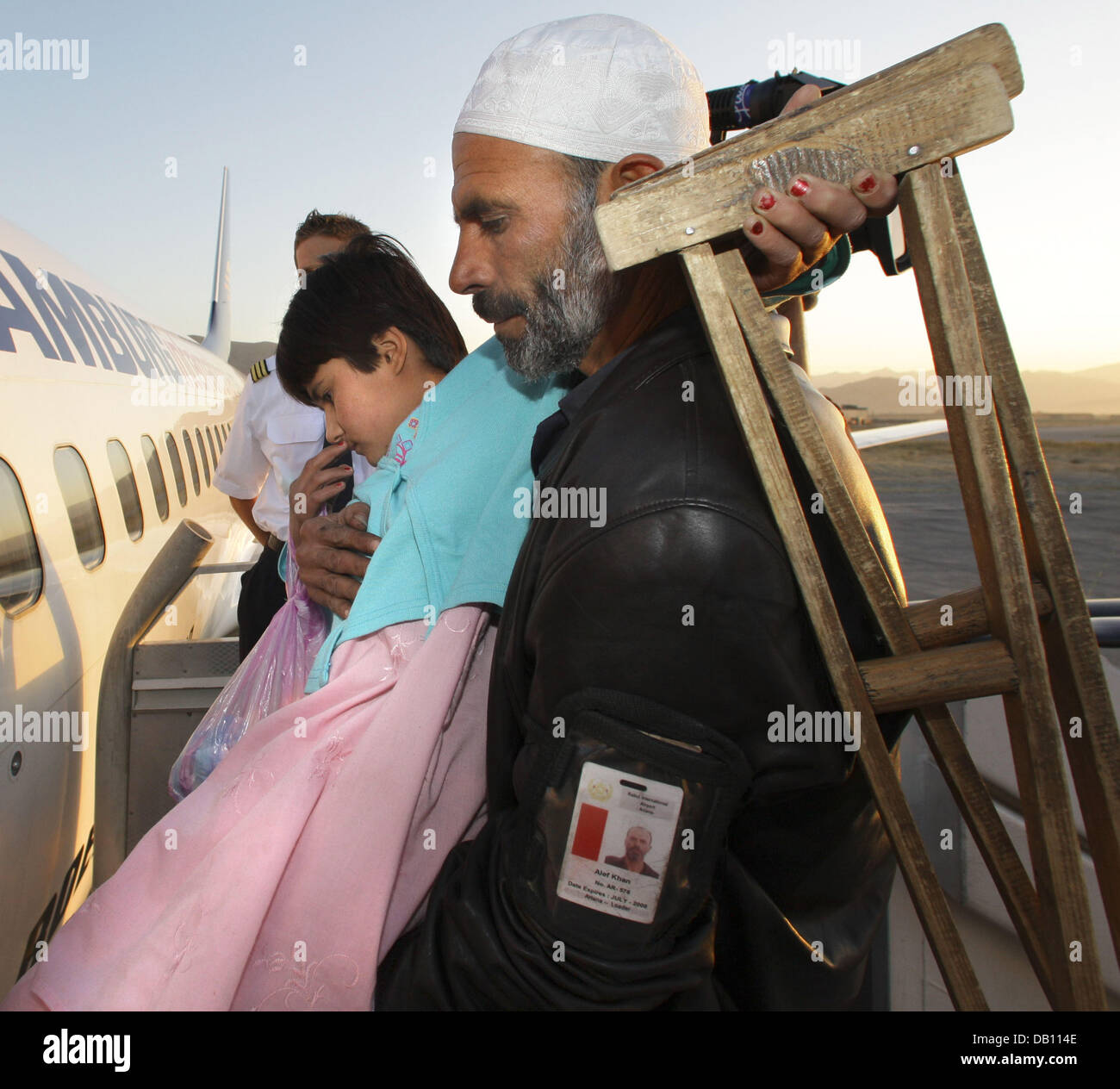 A father carries his eleven-year-old daughter Ramzana on board a plane ...