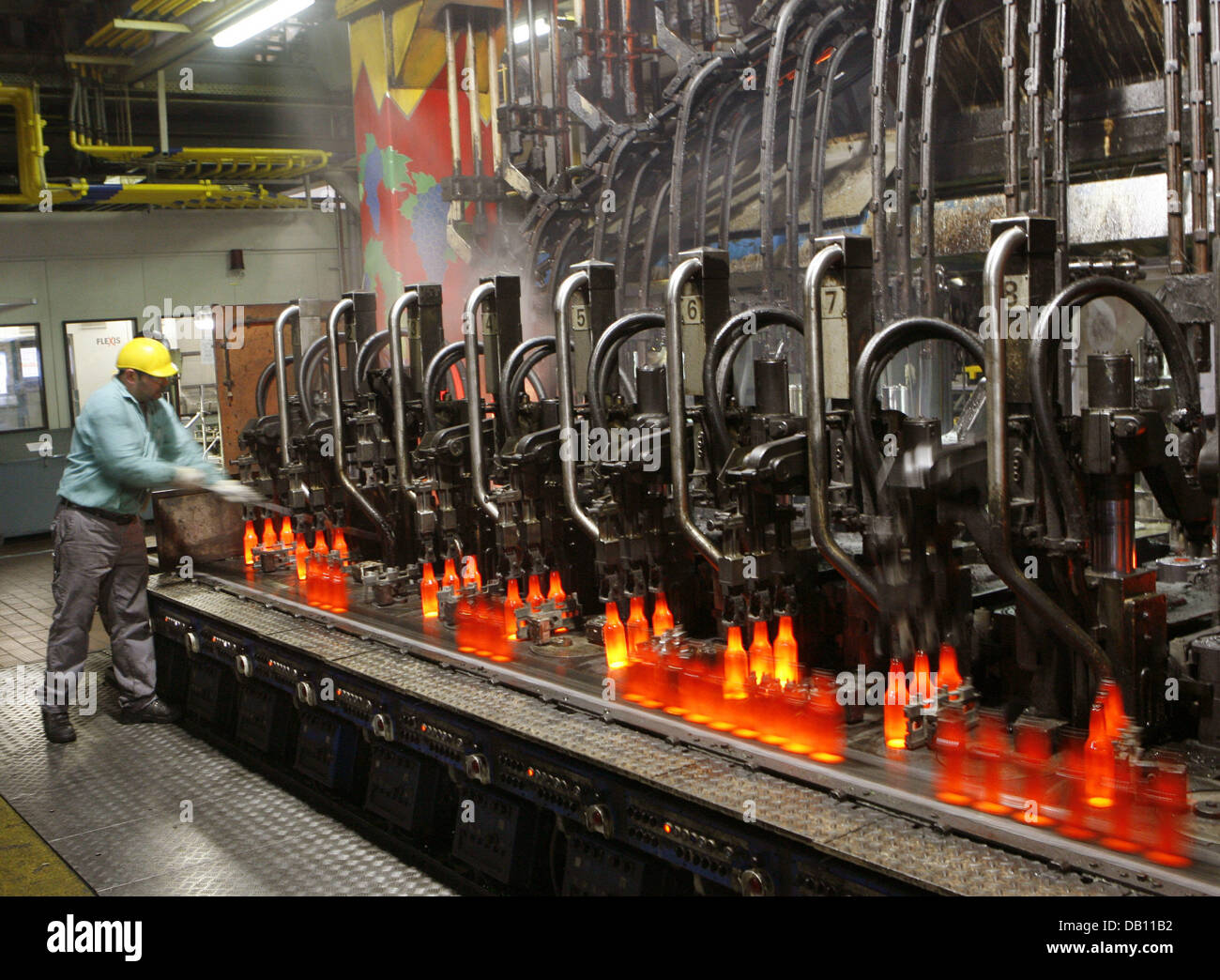 A member of staff checks the production of glass bottles in a ...