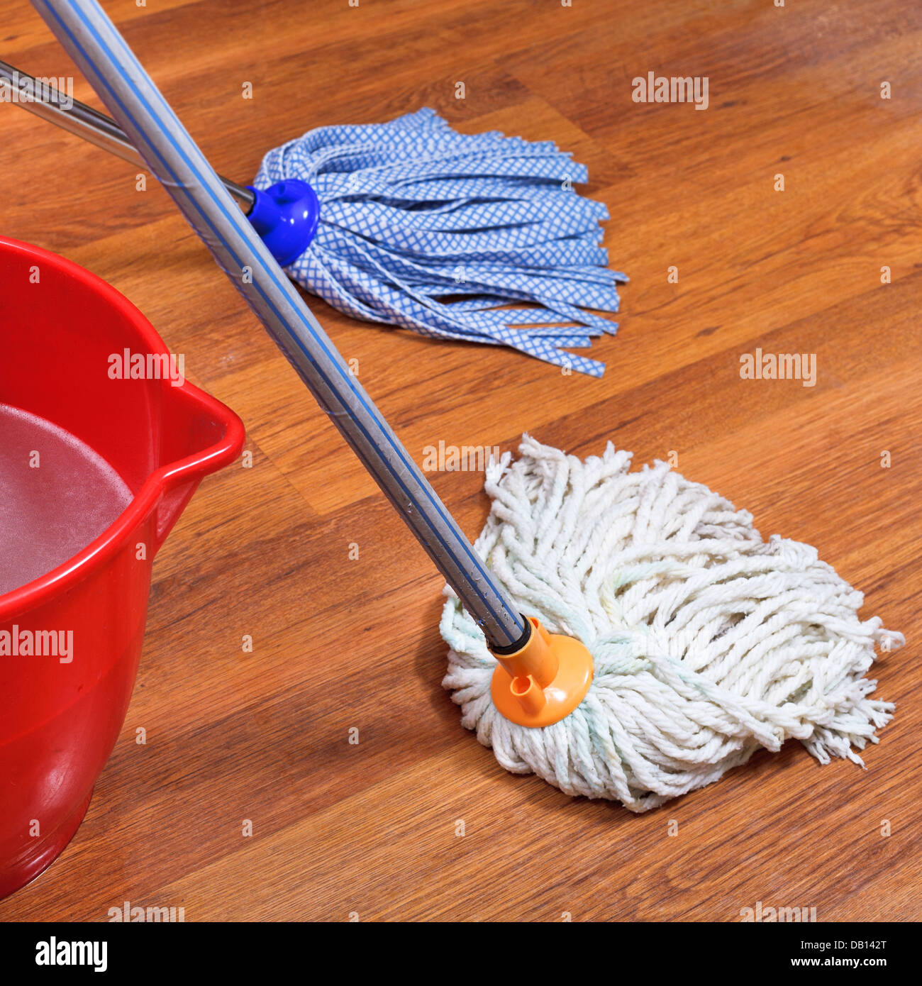 mopping of wood floors by two mops and red bucket Stock Photo - Alamy
