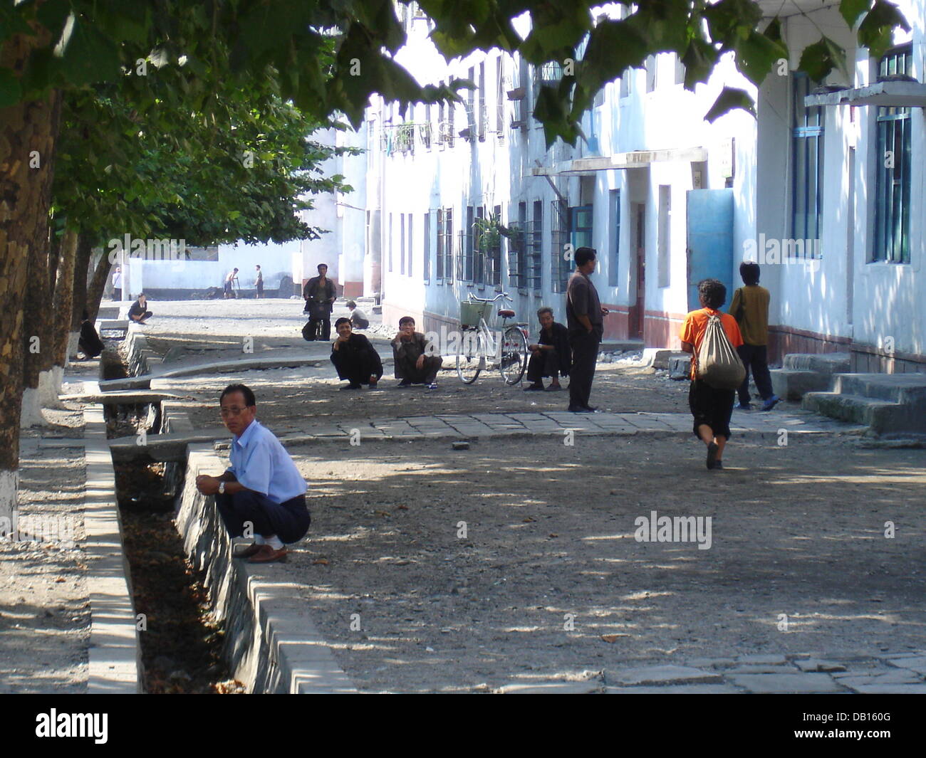 People crouch on the street in front of residential houses in Kujang ...