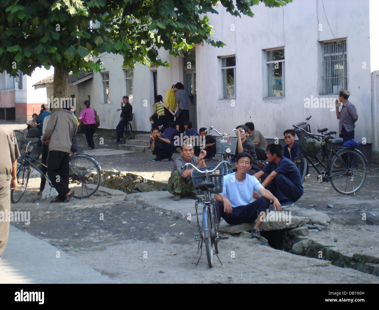 Men crouch on the street in front of residential houses in Kujang ...
