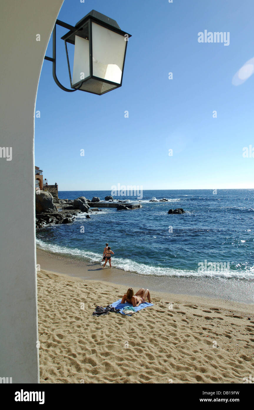 Vacationers enjoy the warm sun at the beach of fishing town Llafranc ...