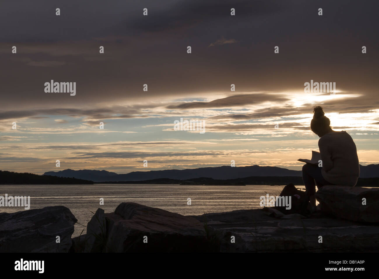 Woman reading a book at sunset Stock Photo - Alamy