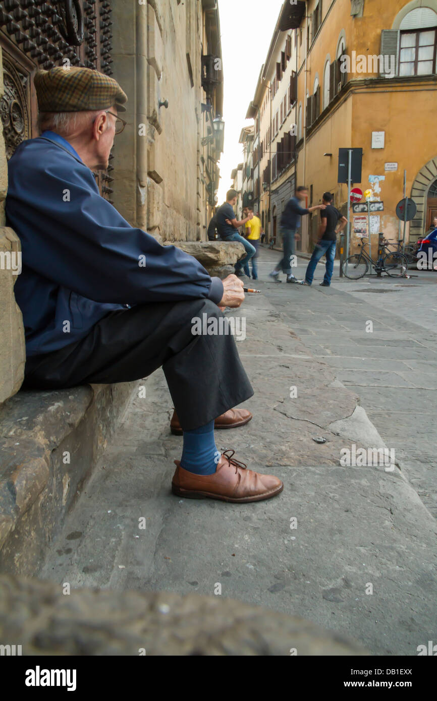 Elderly Italian man watching youths on the street, while smoking a ...