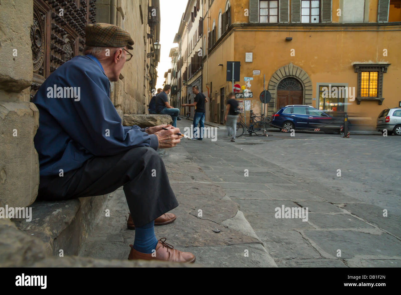 Elderly Italian man watching youths on the street, while smoking a ...