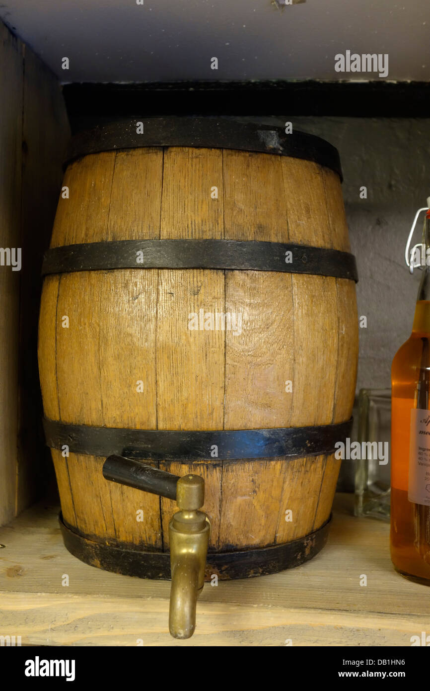A small oak wood barrel placed on the shelf with a bottle by the side ...