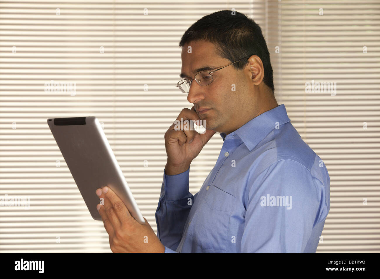 Asian businessman with mobile phone looking at ipad tablet device in ...