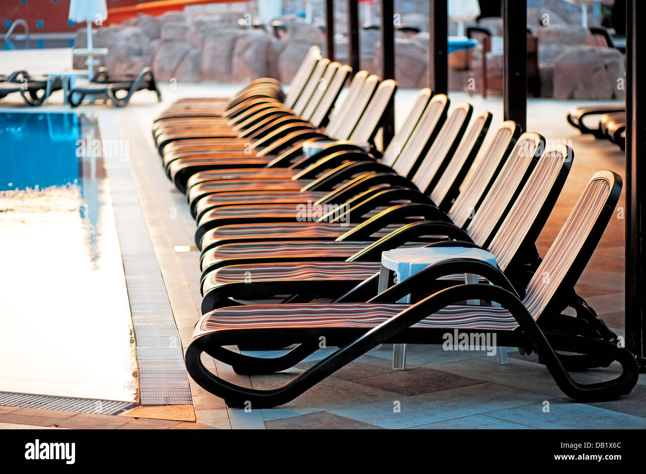 Several of sun loungers by the pool at sunrise Stock Photo - Alamy