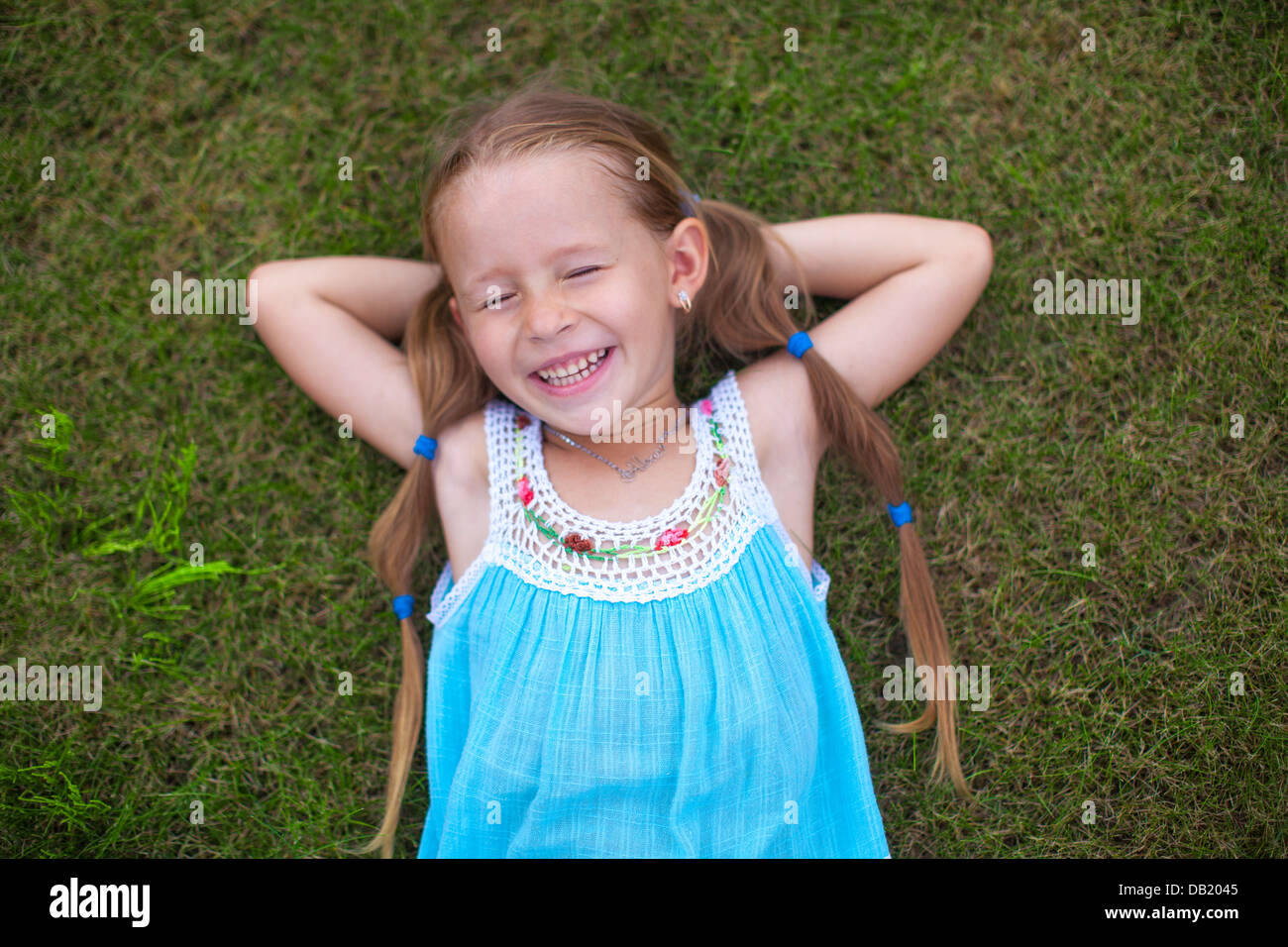 Little girl lying on the grass near the house and laughs Stock Photo ...