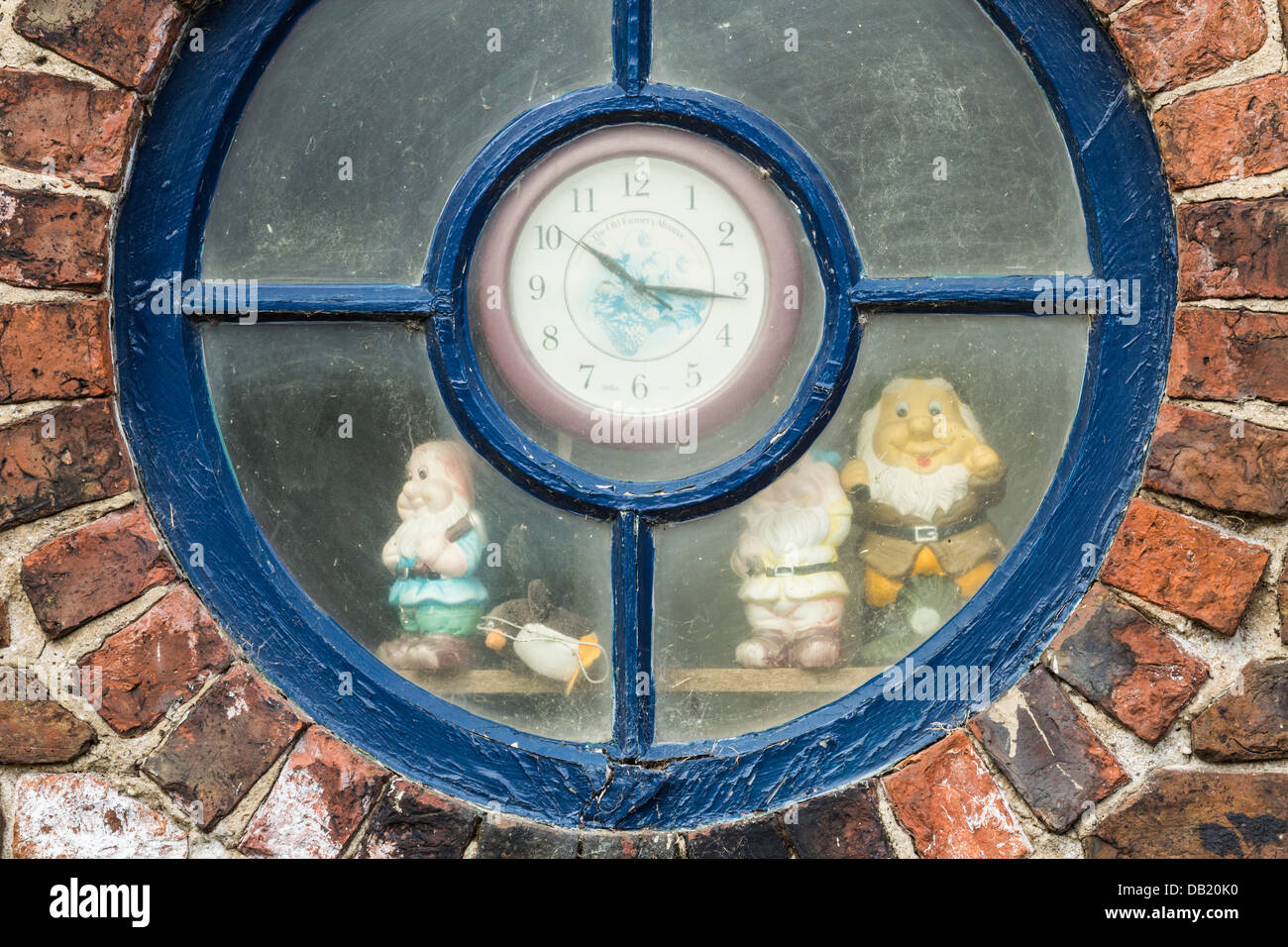 Round window with clock in centre and garden gnomes looking out of ...
