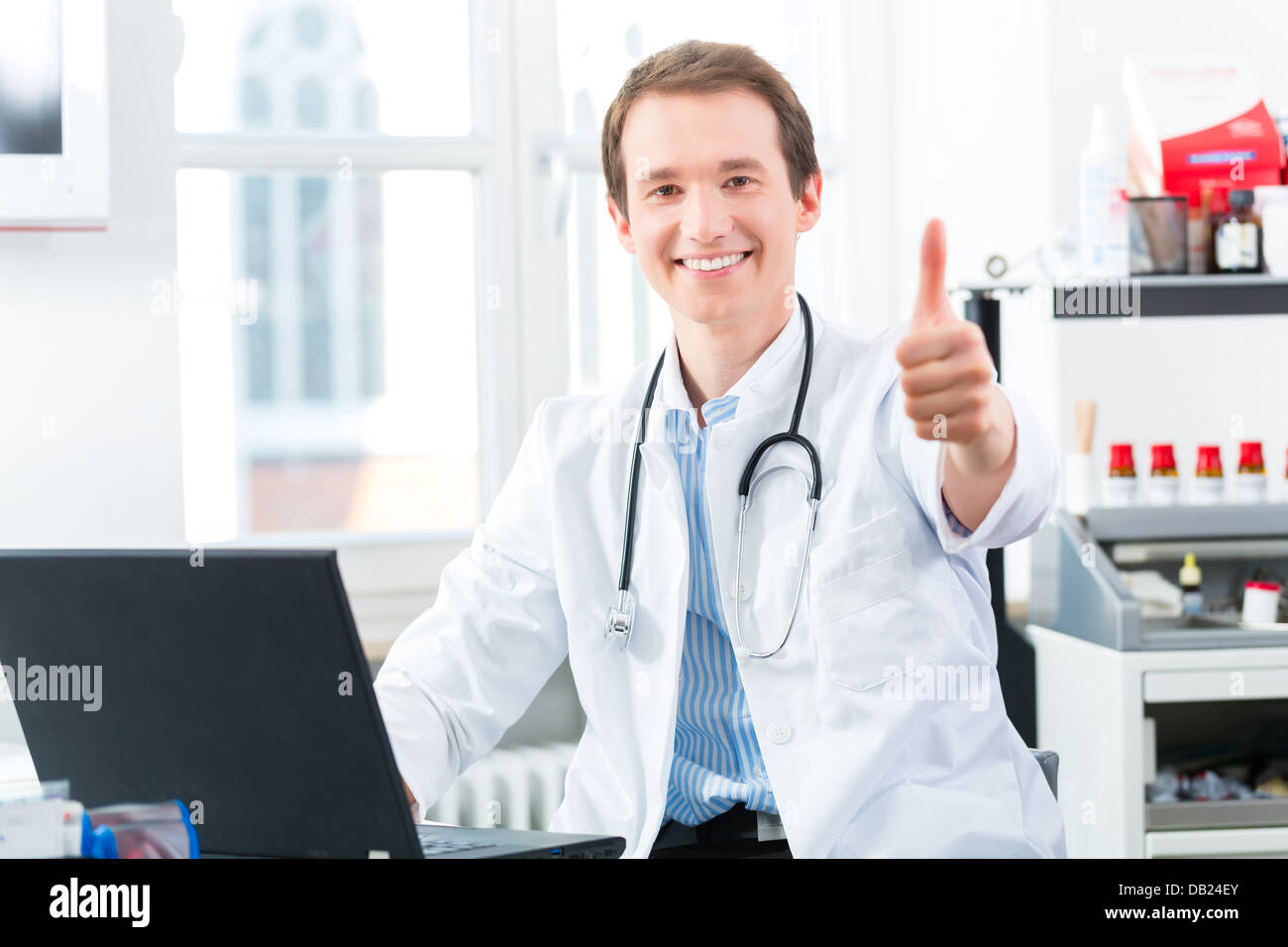 Young doctor sitting at a desk in front of window in clinic on a ...
