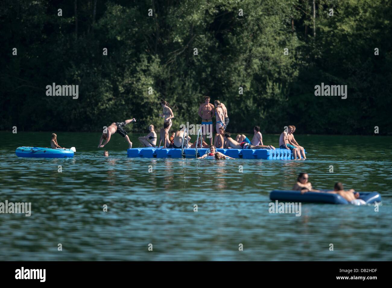 Young people refresh themselves on a swimming platform on Roither See ...