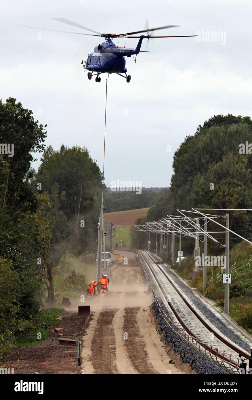 A helicopter transports the catenary posts to a construction site of ...