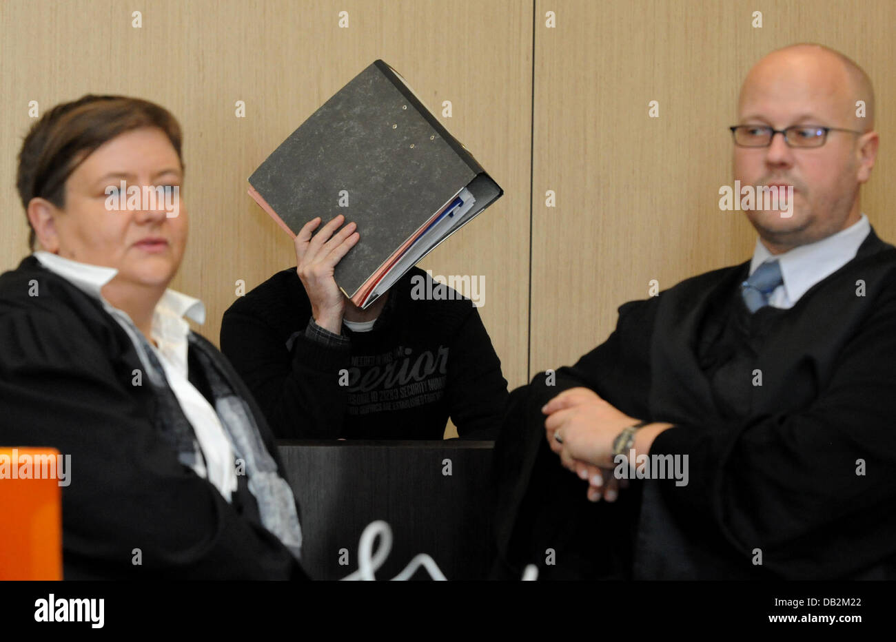 The 40-years-old defendant covers his face with a file next to his ...